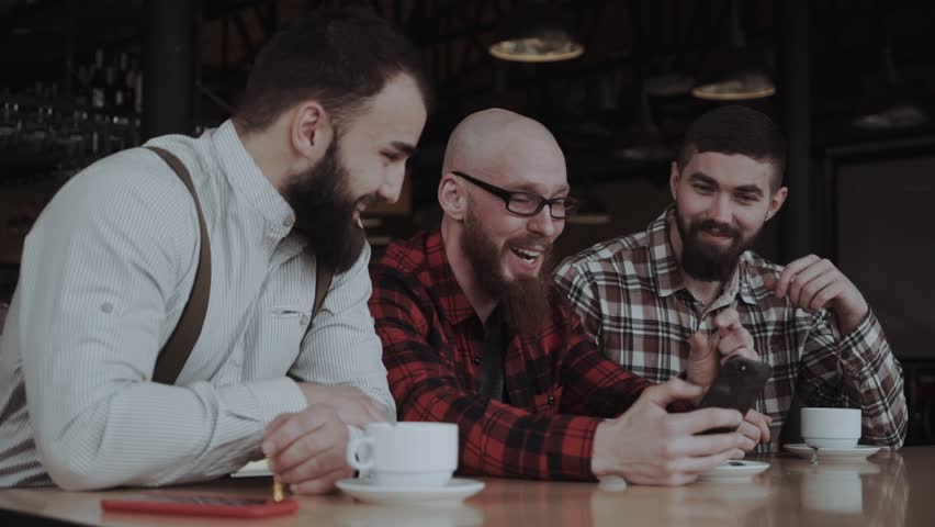 Three Handsome Young Men Are Drinking Coffee, Talking And Laughing ...