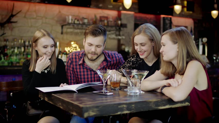 Happy Young People Sitting In The Bar Reading Menu Card And Giving ...