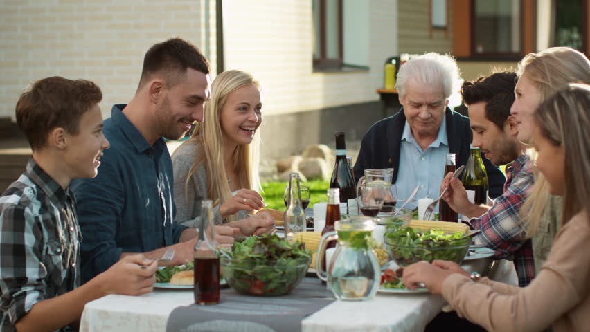 Group Of People Sitting Around A Table, Eating, Communicating And ...