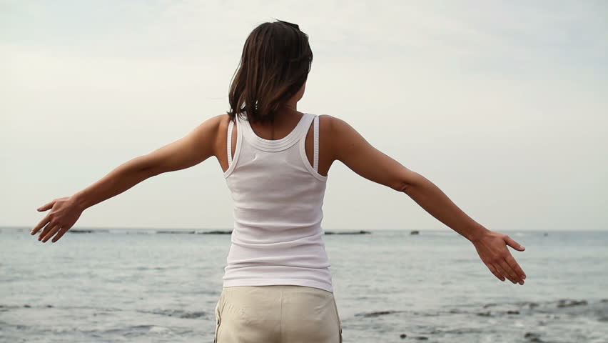 Young Woman With Arms Wide Open Standing At The Beach, Camera ...