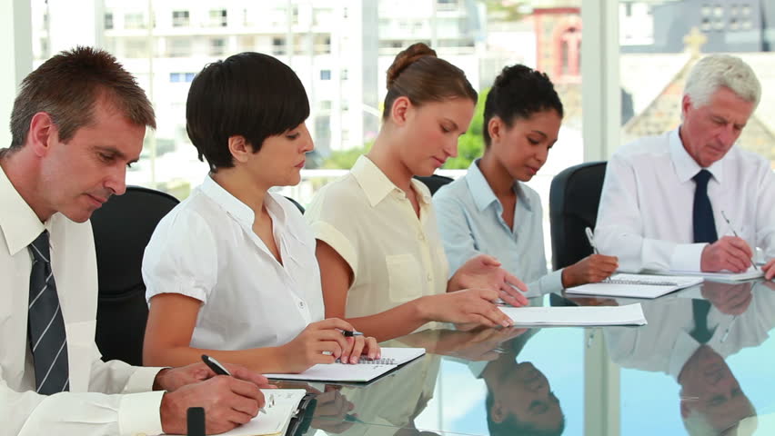 Business People Taking Notes While Sitting At A Meeting Table In A ...