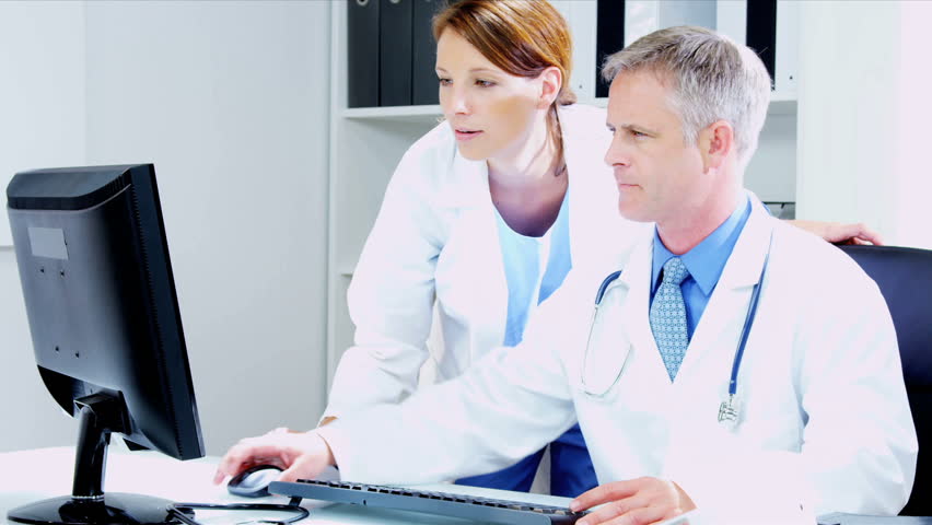 Caucasian Male Medical Consultant With Young Female Doctor Updating ...